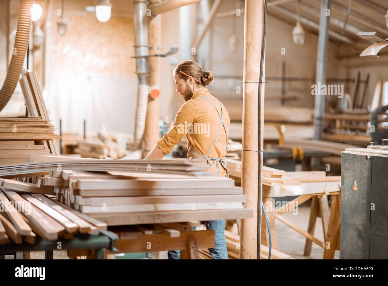 Carpenter carrying pine planks in a carpentry workshop warehouse ...