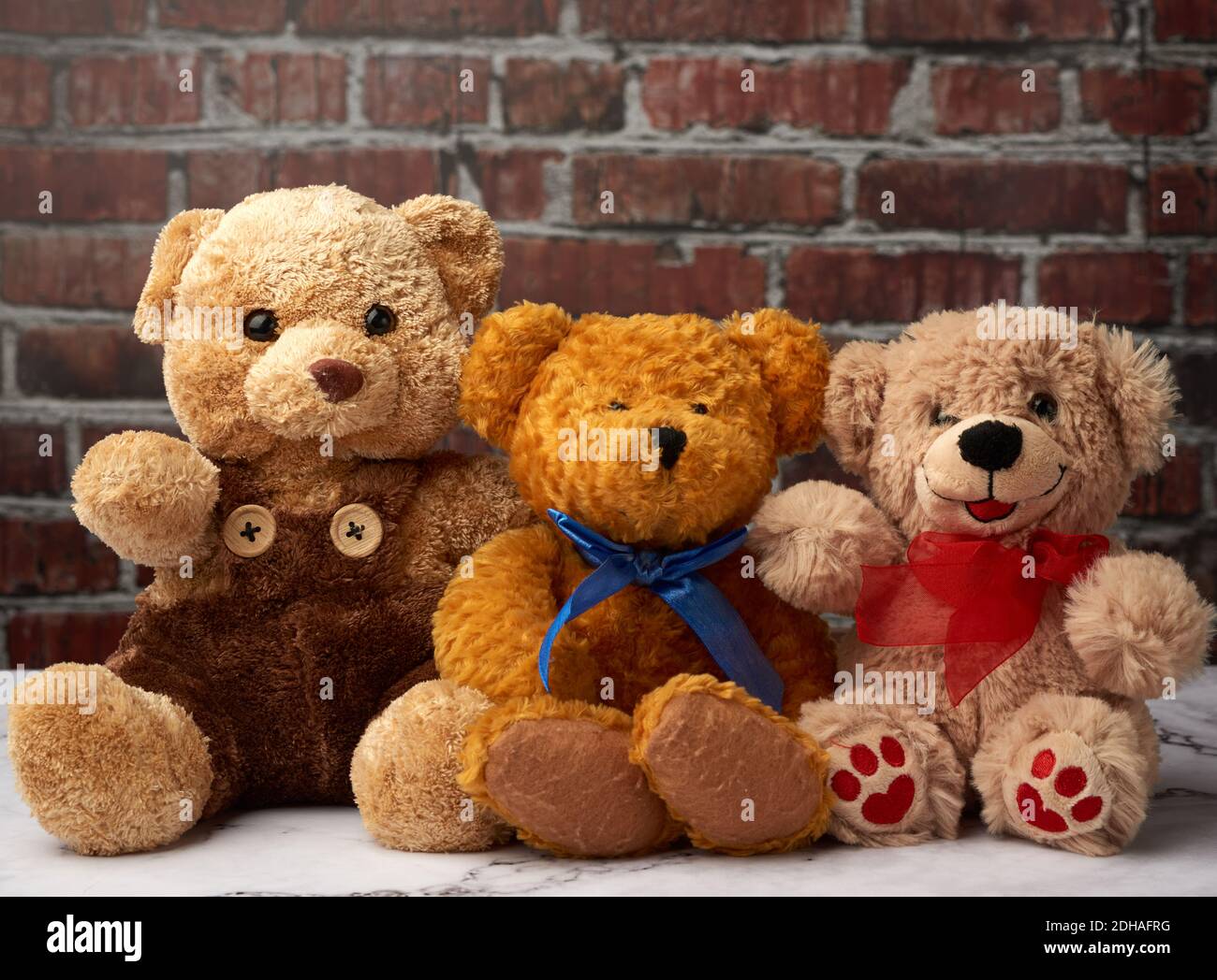 Brown teddy bear sits on a table, behind brown brick wall Stock Photo ...