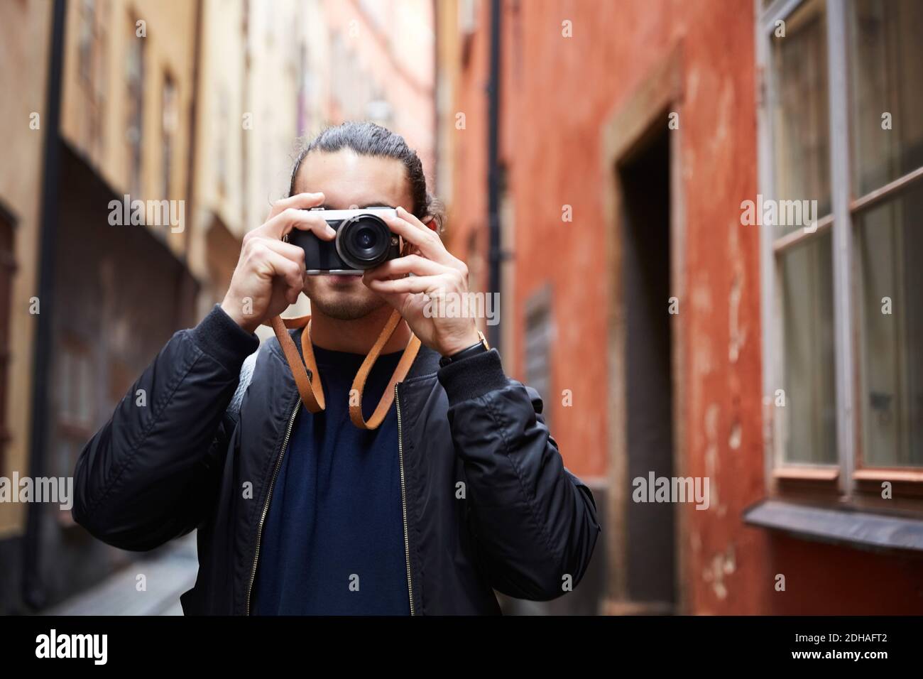 Man photographing through camera while standing against buildings Stock ...