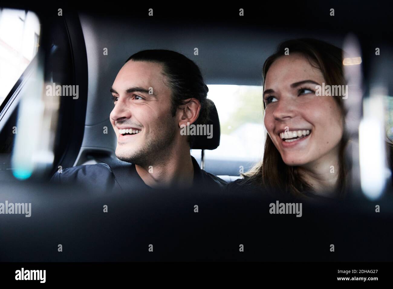 Smiling young friends looking through window while riding in taxi Stock ...