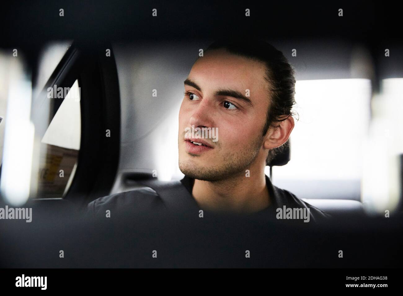Close-up of thoughtful young man looking through window while riding ...