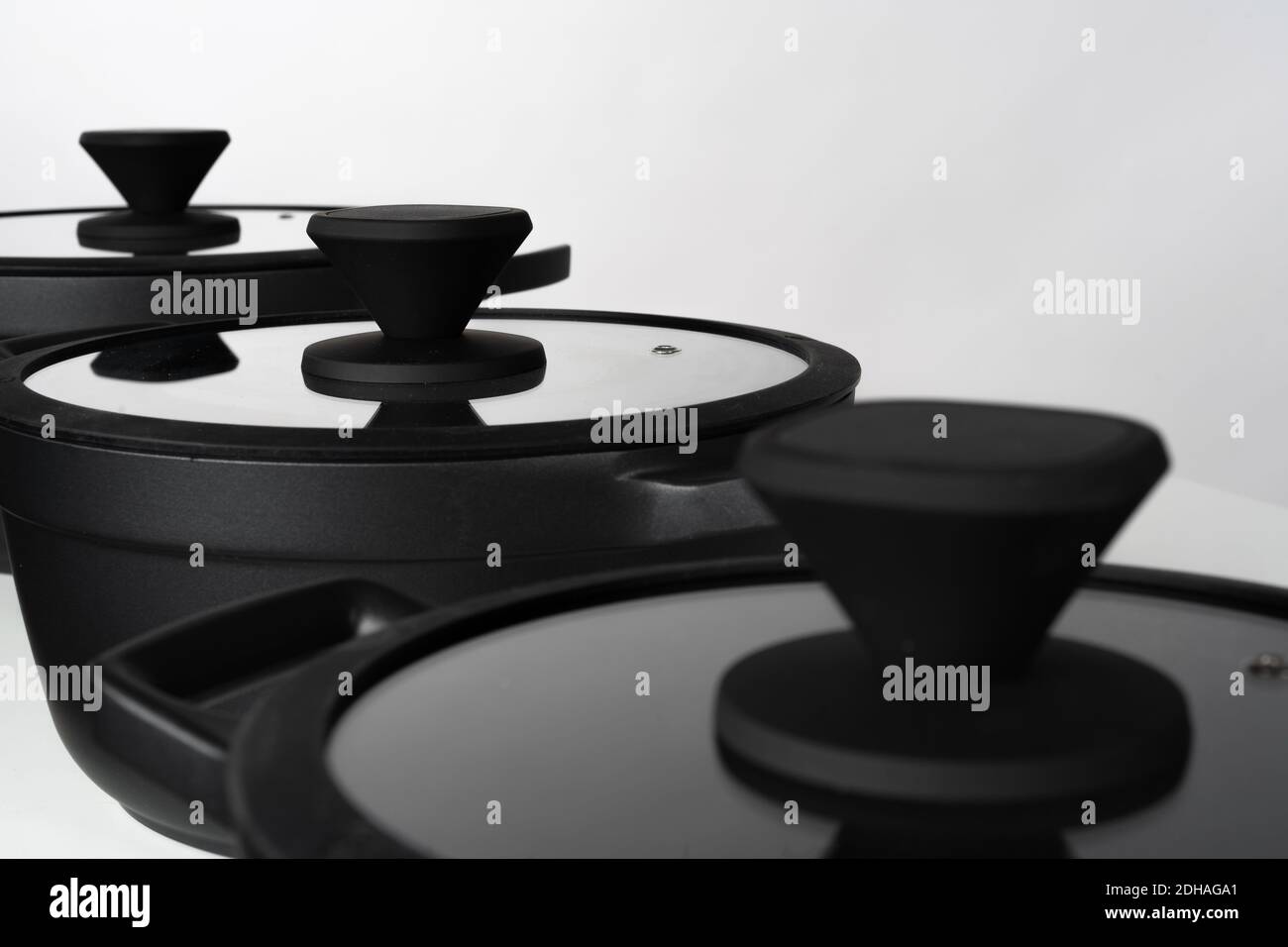 Black cooking pots on grey background front view Stock Photo - Alamy