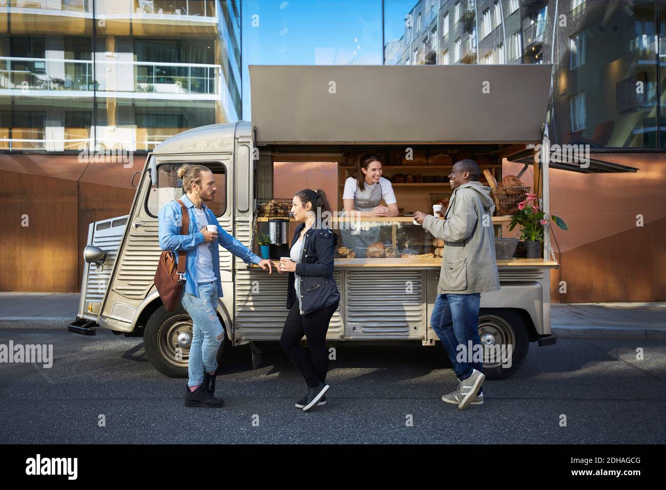 Female owner in concession stand while customers having food and drink ...
