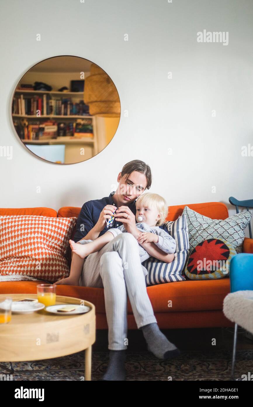 Full length of father and son playing with toy car while sitting on ...