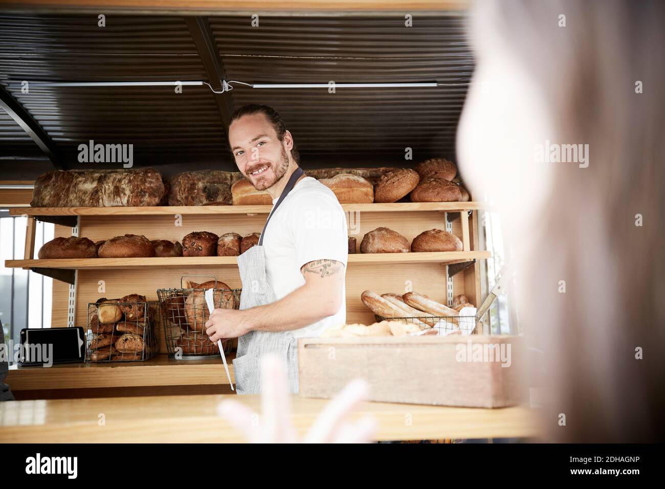 Smiling male owner selling fresh breads in concession stand Stock Photo ...