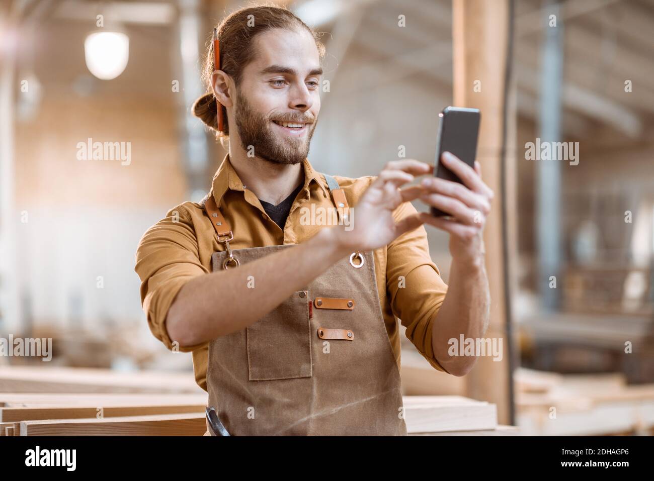Handsome carpenter talking on smart phone or using phone to design some ...