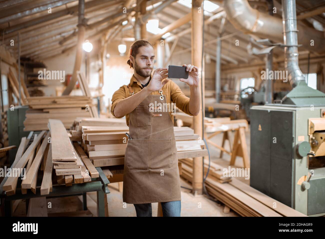 Handsome carpenter talking on smart phone or using phone to design some ...