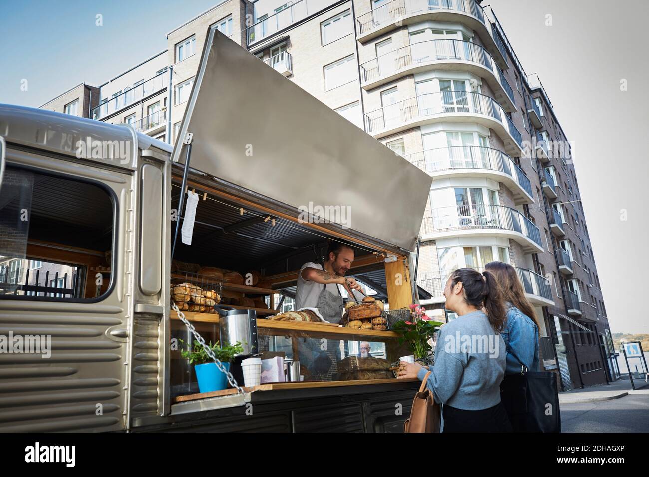 Female customers buying bread from salesman at food truck in city Stock ...