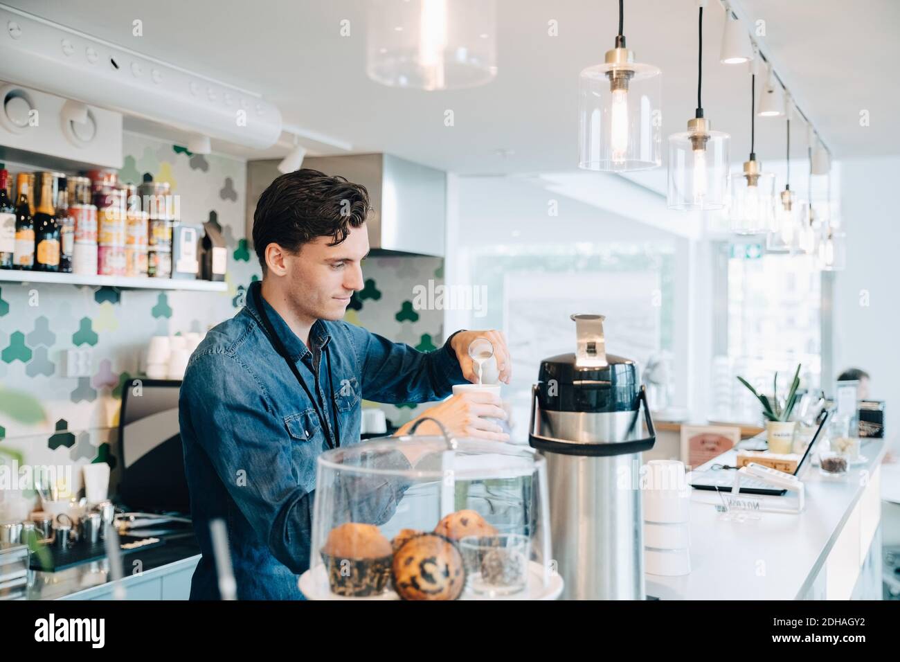 Young owner making coffee at checkout counter in office cafe Stock ...