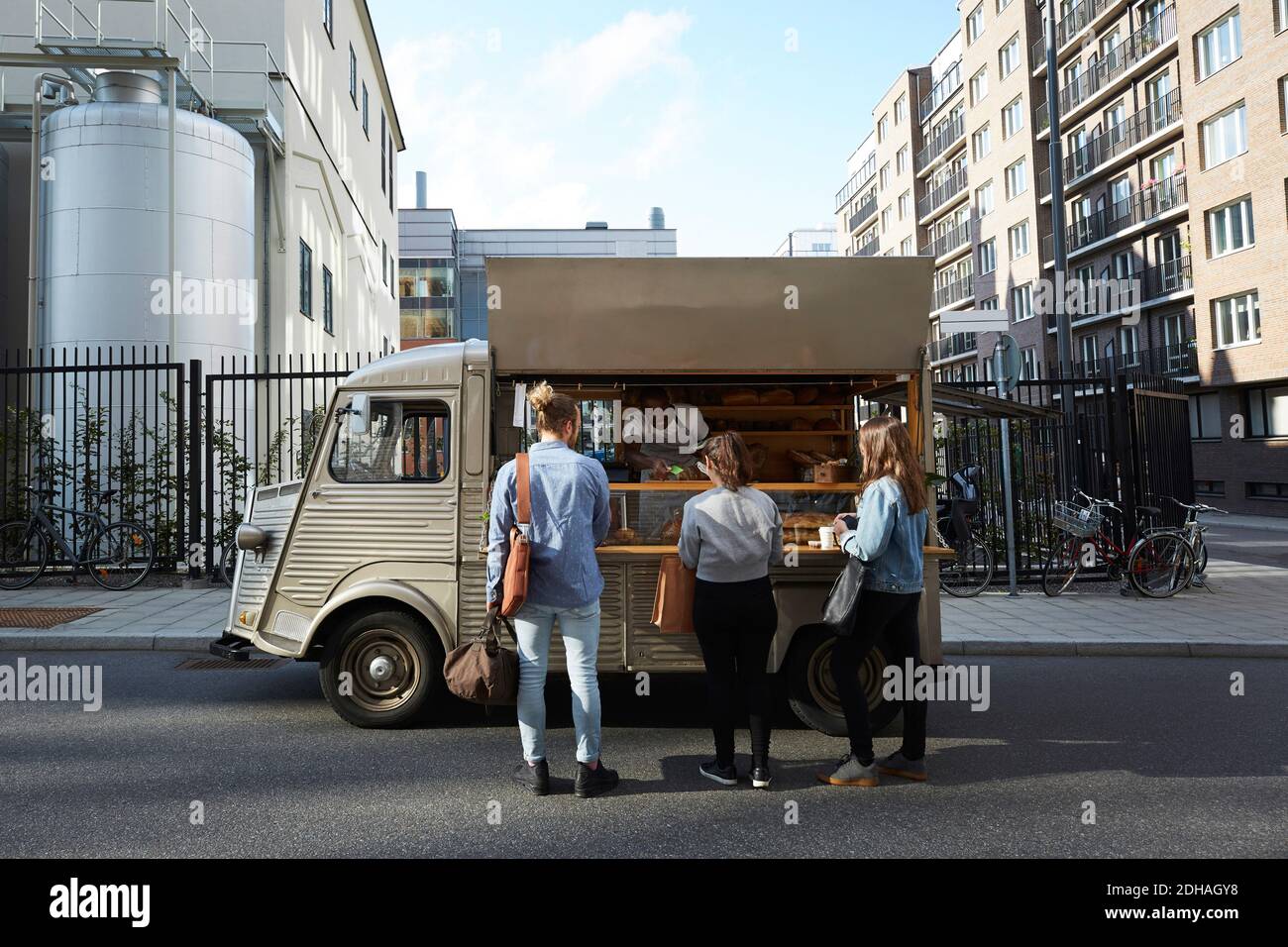 Customers buying bread from salesman at food truck parked on city ...