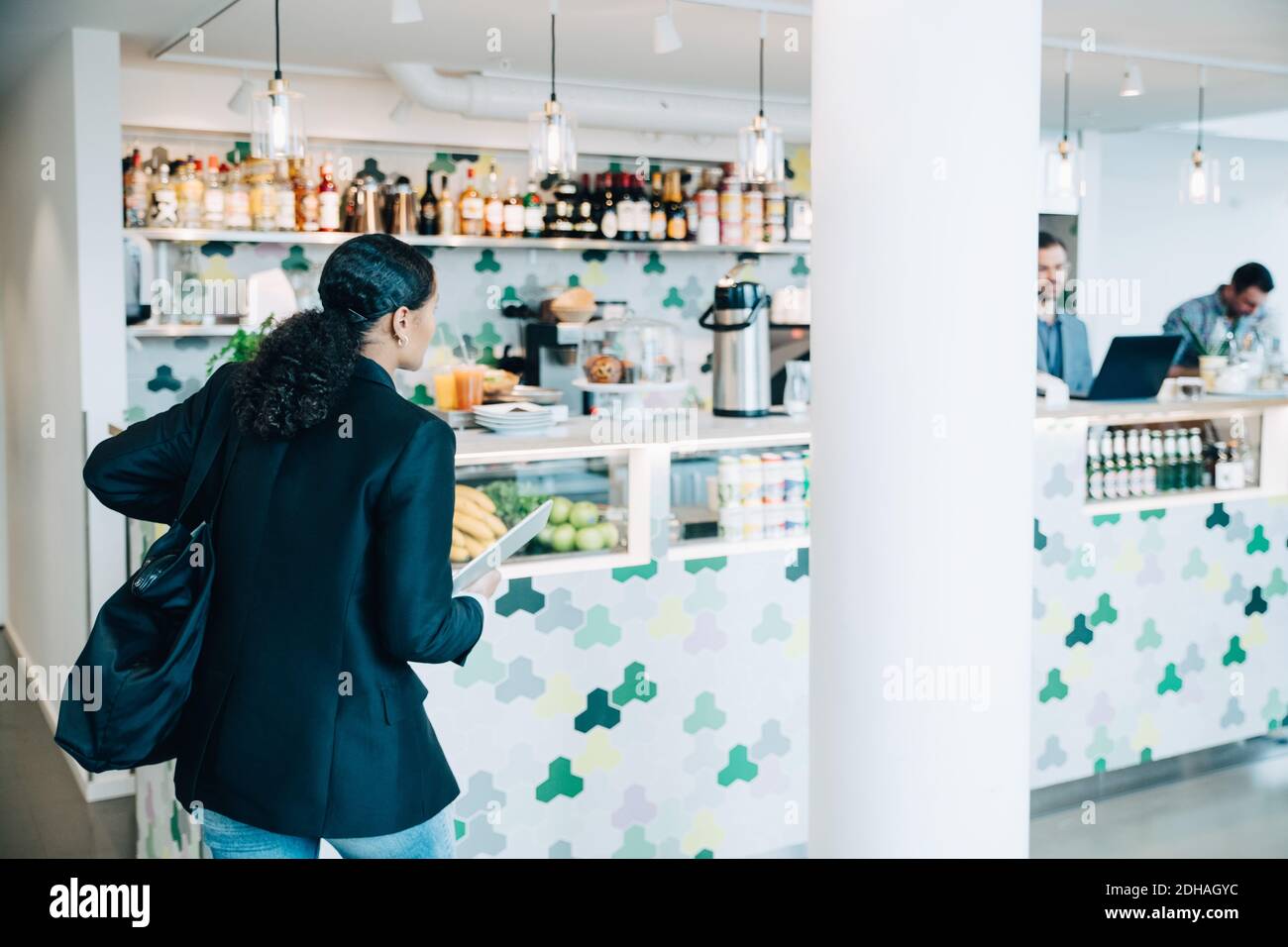 Businesswoman with laptop walking towards checkout counter in cafe ...