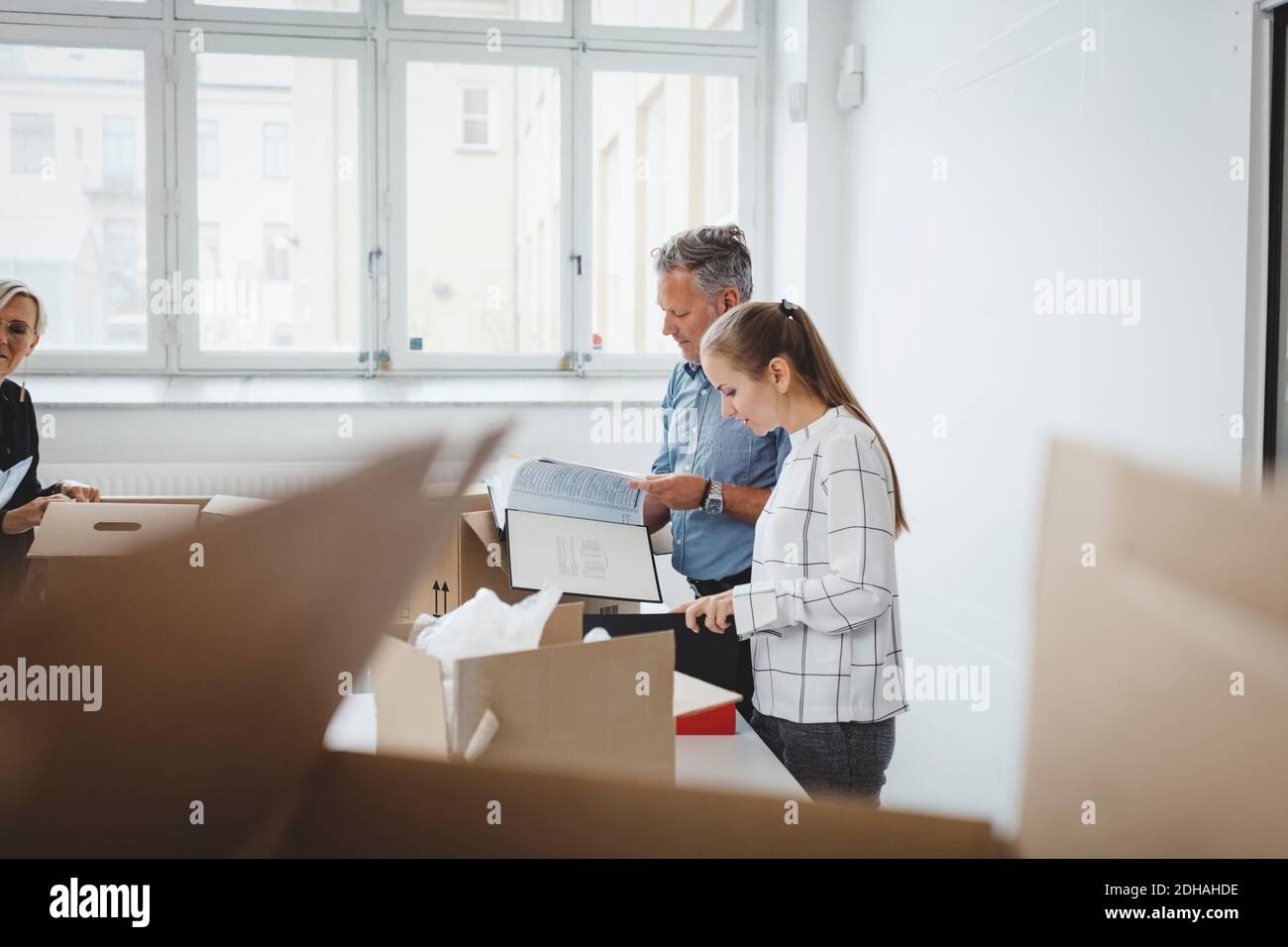Business people unpacking moving boxes at table in new office Stock ...