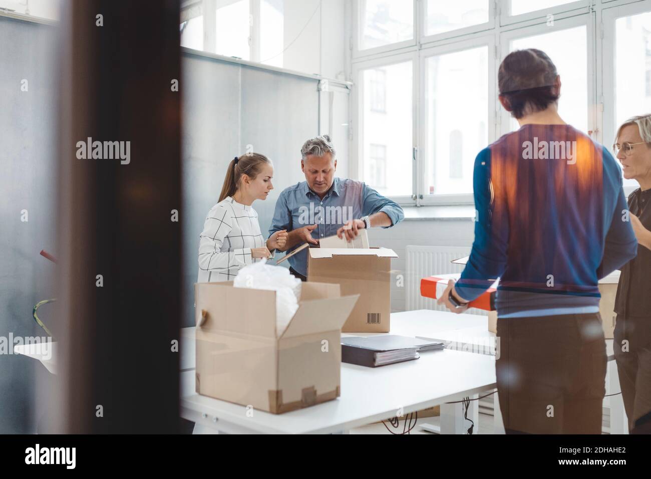 Business people unpacking cardboard boxes in new office seen through ...