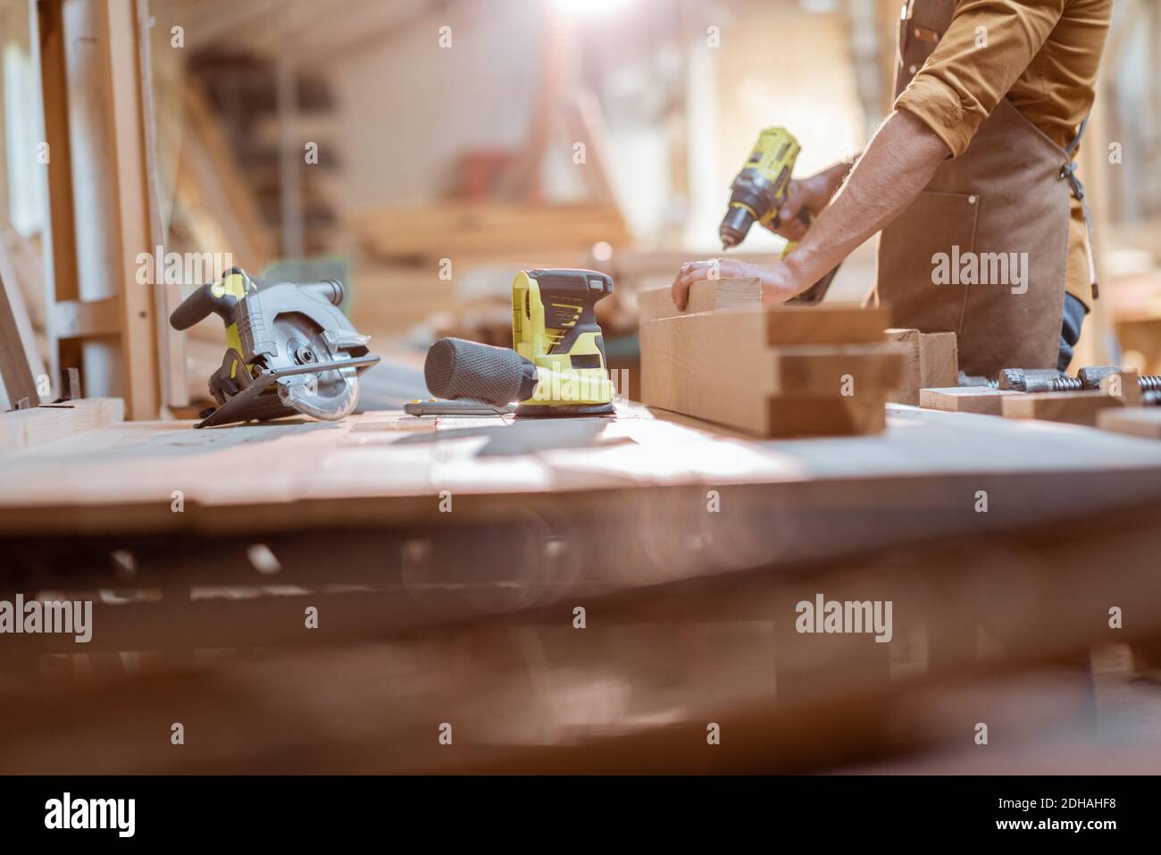 Carpenter working with modern cordless tools and wooden bars on the ...