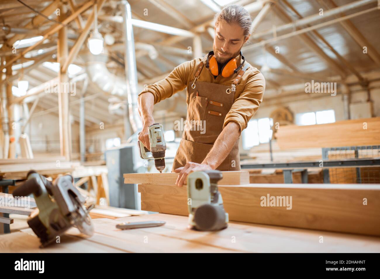 Carpenter working with modern cordless tools and wooden bars on the ...