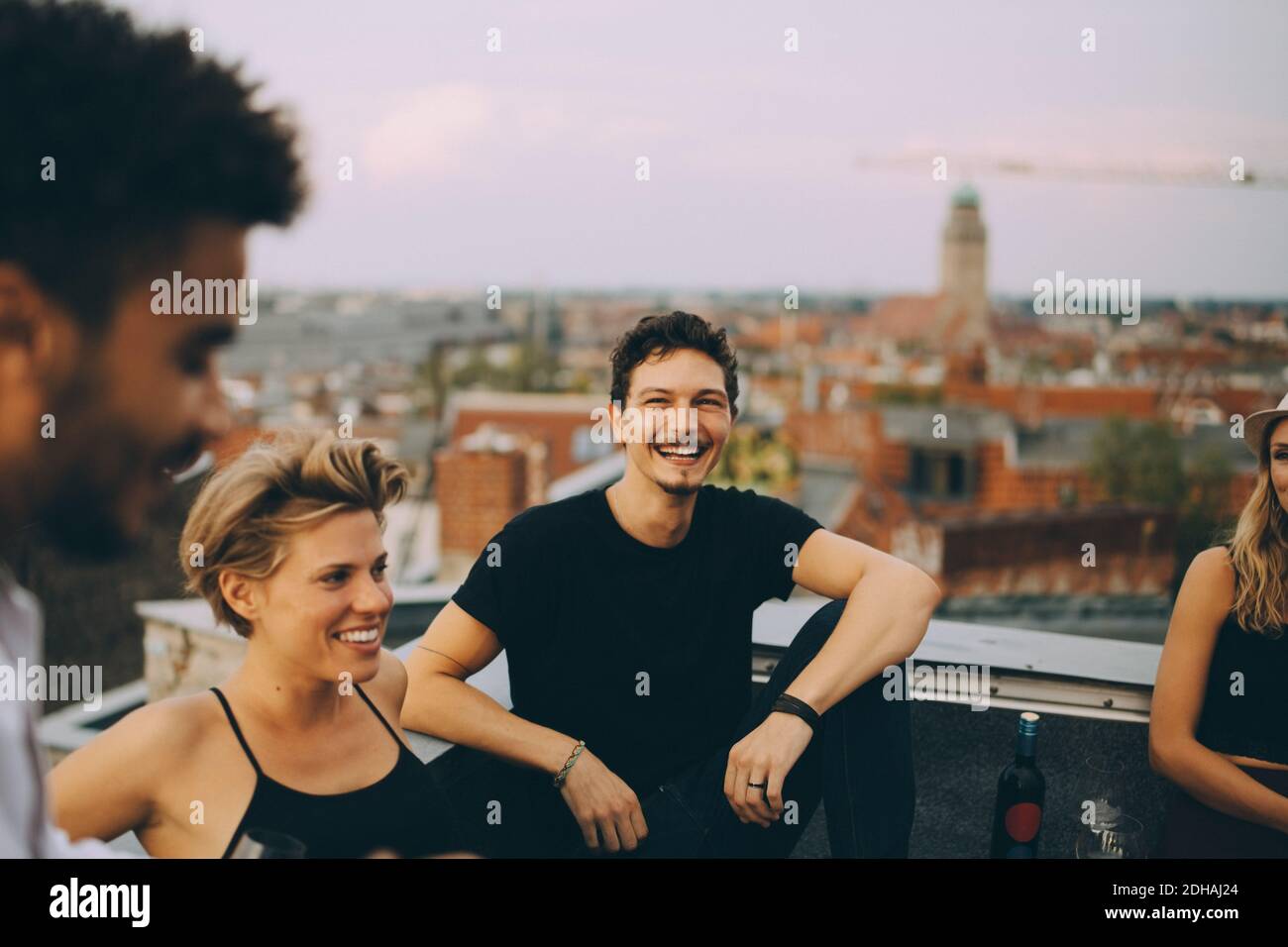 Happy friends enjoying at rooftop party against cityscape Stock Photo ...