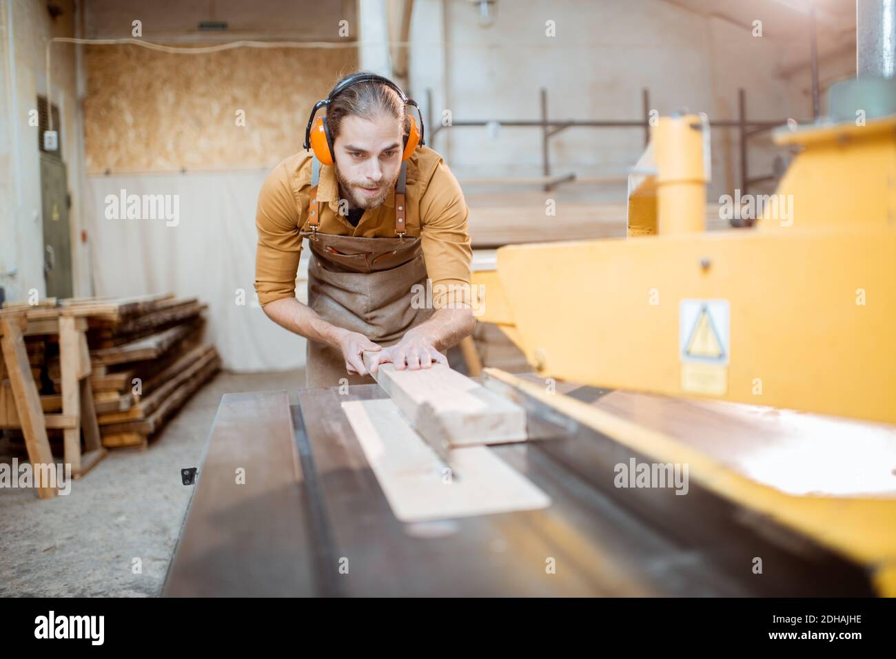 Carpentry worker sawing wooden planks with circular saw in the joinery ...