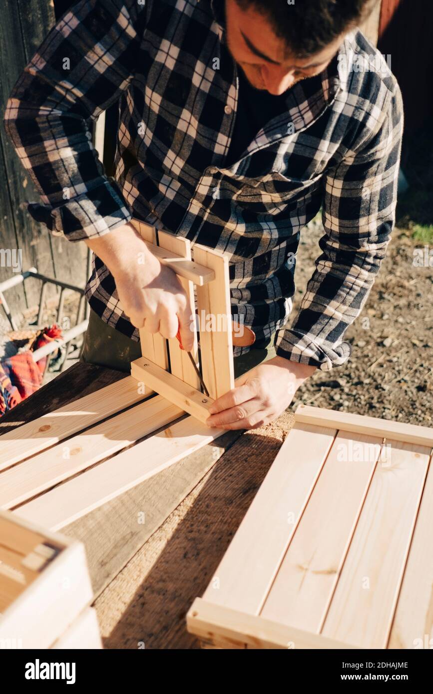 Mid adult male farmer making wooden crate using screwdriver Stock Photo ...