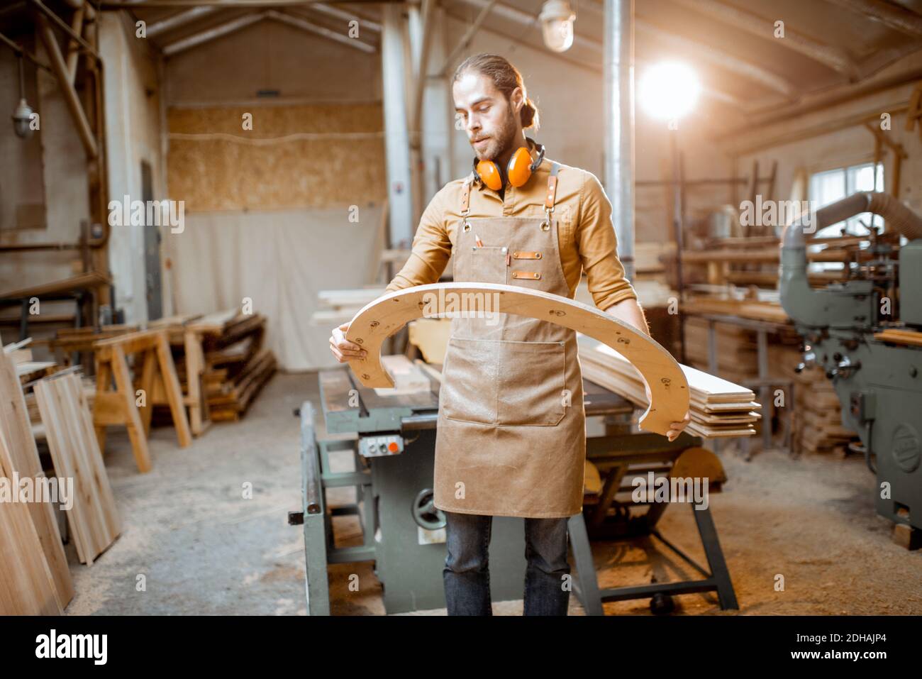 Portrait of a handsome carpenter looking on the wooden product ...