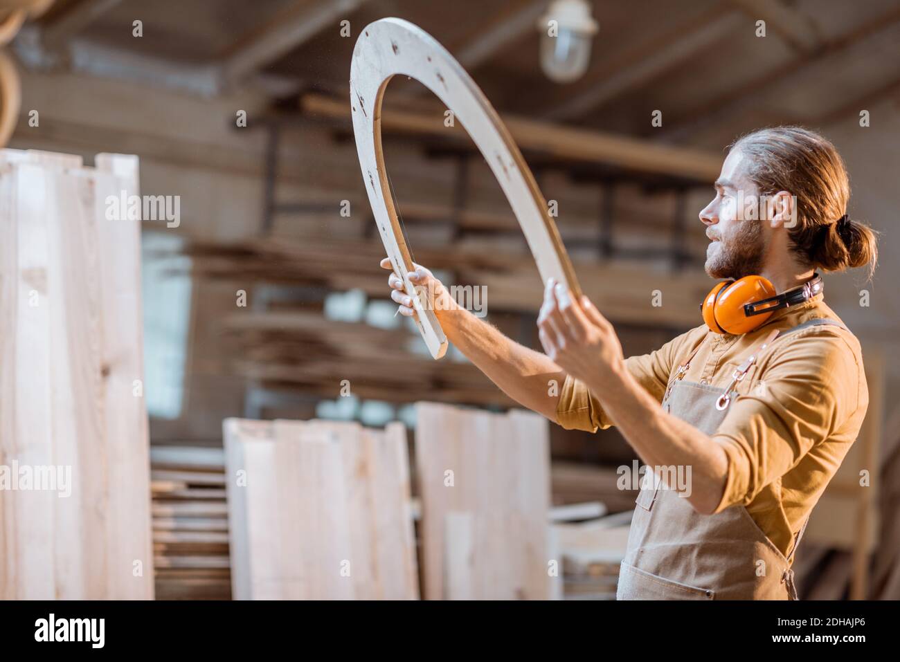 Portrait of a handsome carpenter looking on the wooden product ...