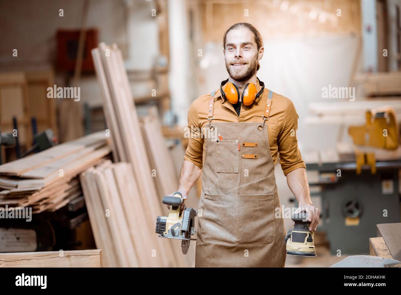 Portrait of a handsome carpenter in uniform with modern tools at the ...