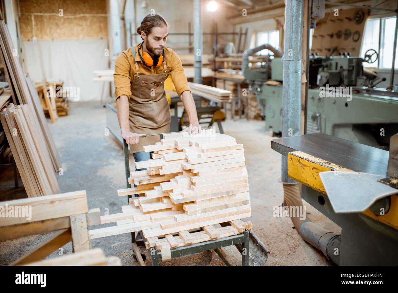 Carpentry worker pushing cart full of wooden planks at the joinery ...
