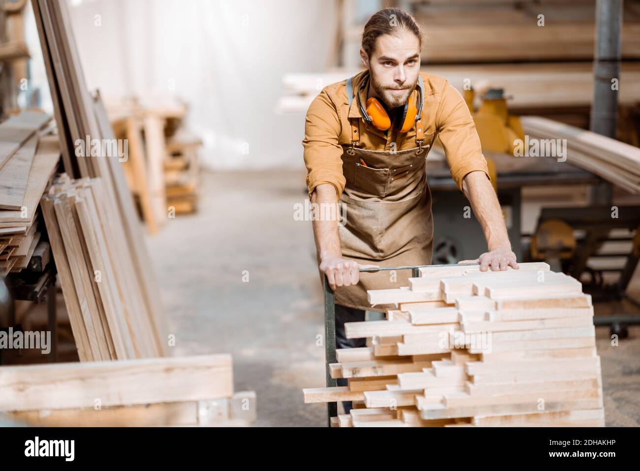 Carpentry worker pushing cart full of wooden planks at the joinery ...