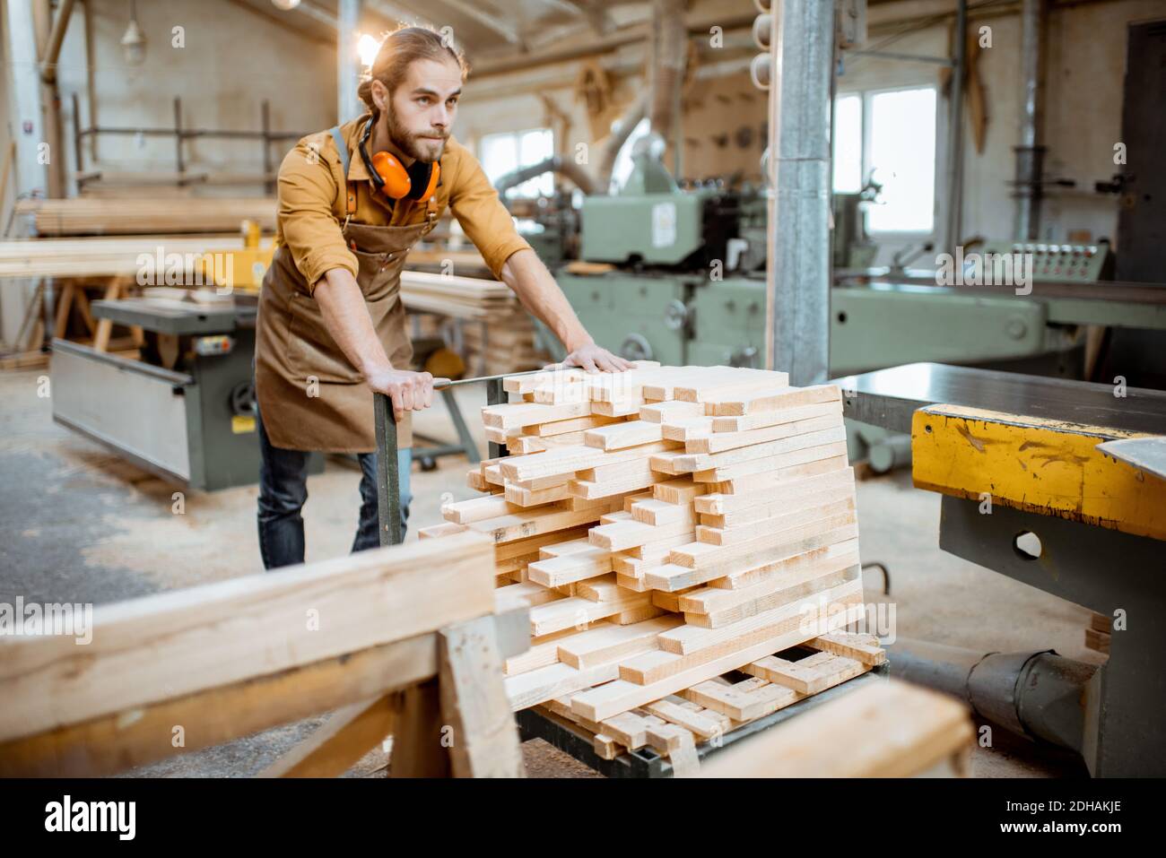 Carpentry worker pushing cart full of wooden planks at the joinery ...