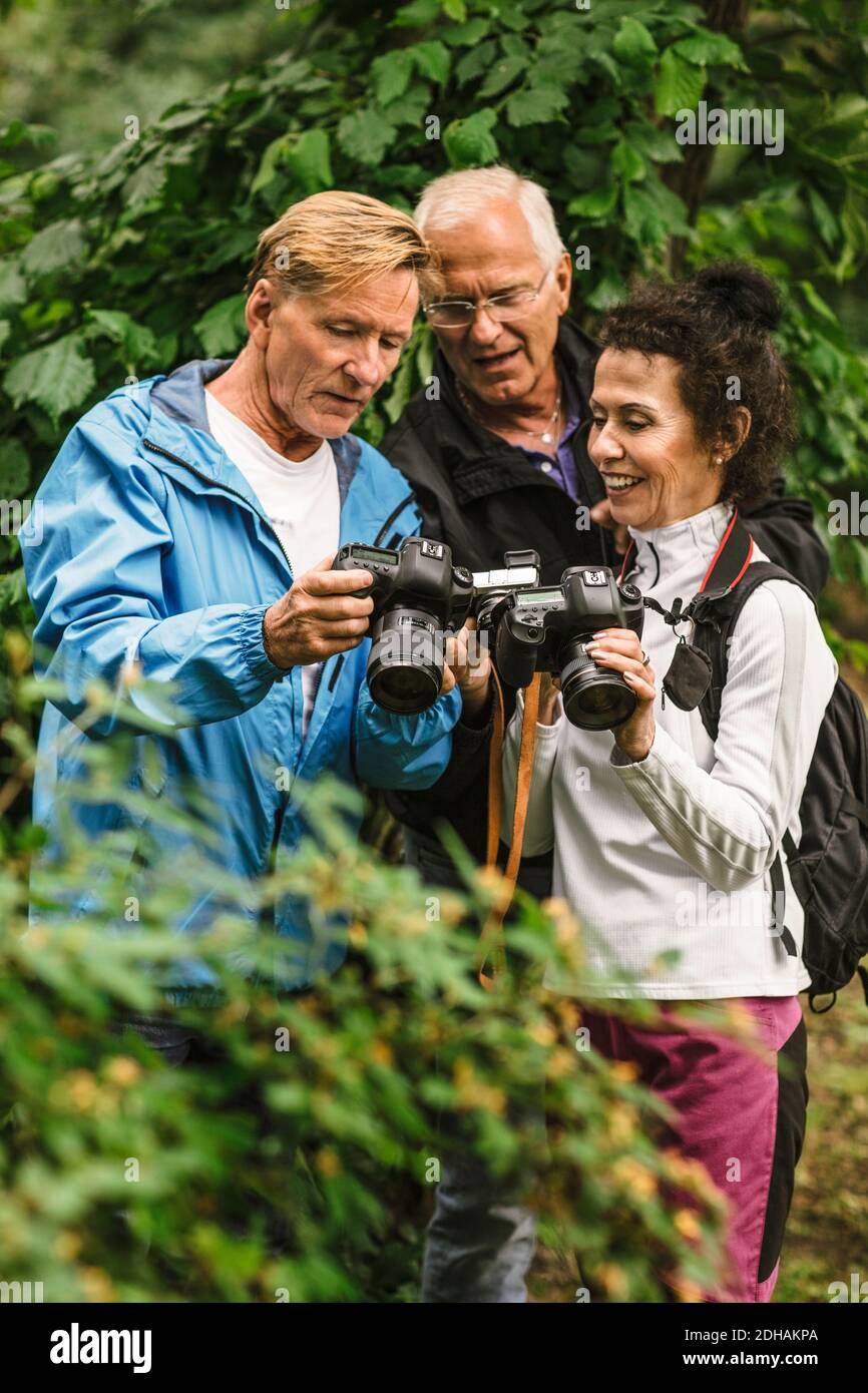 Senior man showing camera to female instructor and friend during ...
