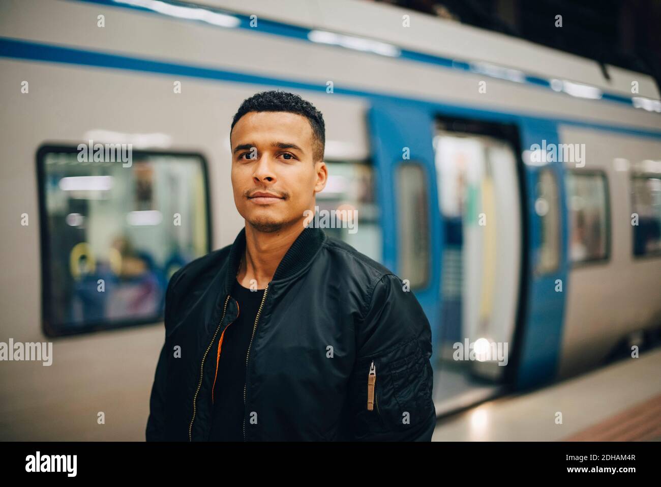 Portrait of man standing by train at subway station Stock Photo - Alamy