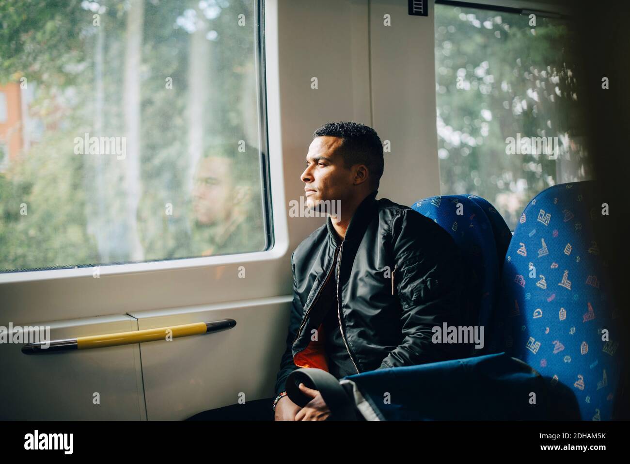 Thoughtful man looking through window while sitting in train Stock ...