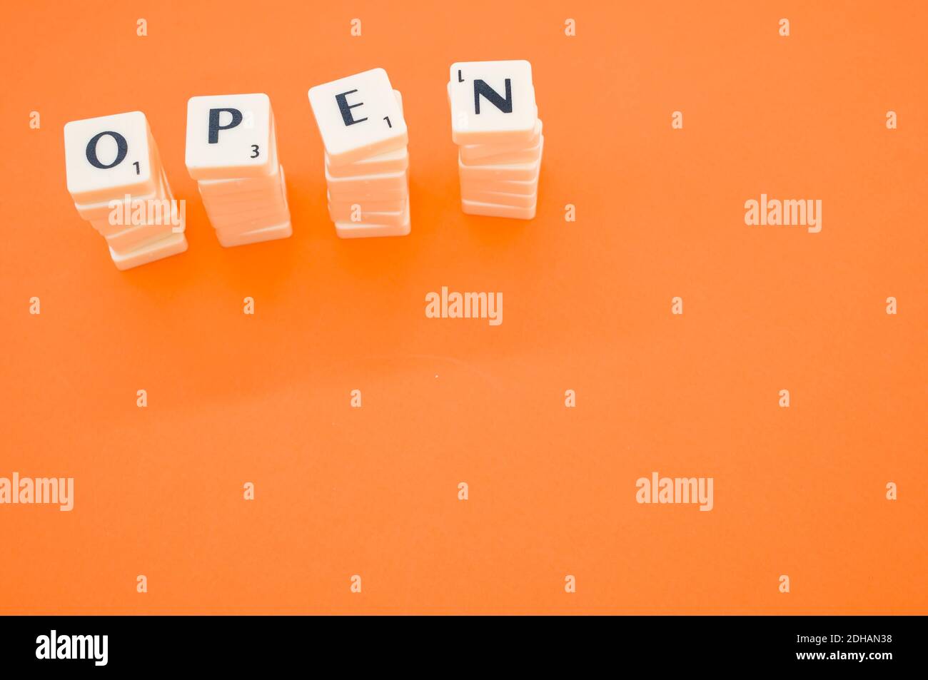 The four white letter block stacks forming the word OPEN on an orange ...