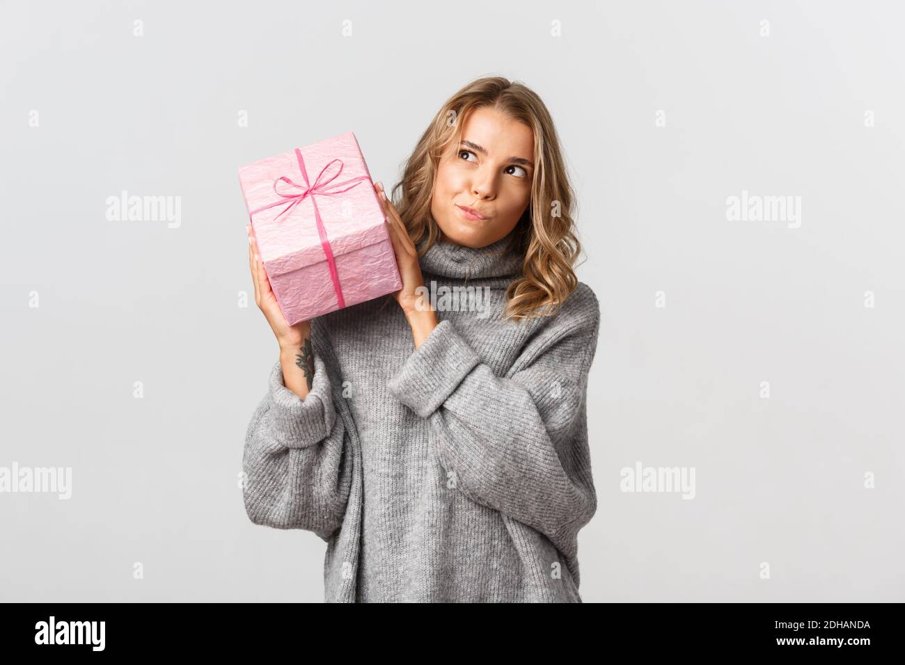 Image of cute blond girl shaking box with a gift, trying to guess what ...
