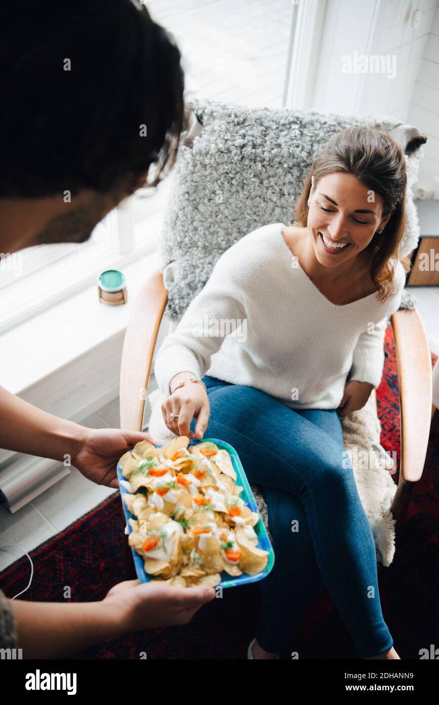 Smiling woman taking snacks from friend during party at home Stock ...