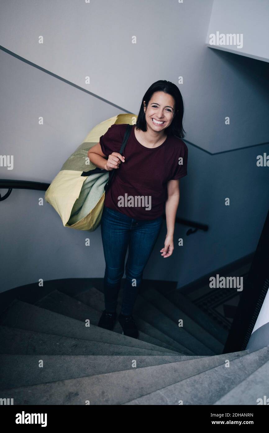 High angle portrait of smiling woman carrying bag while standing on ...