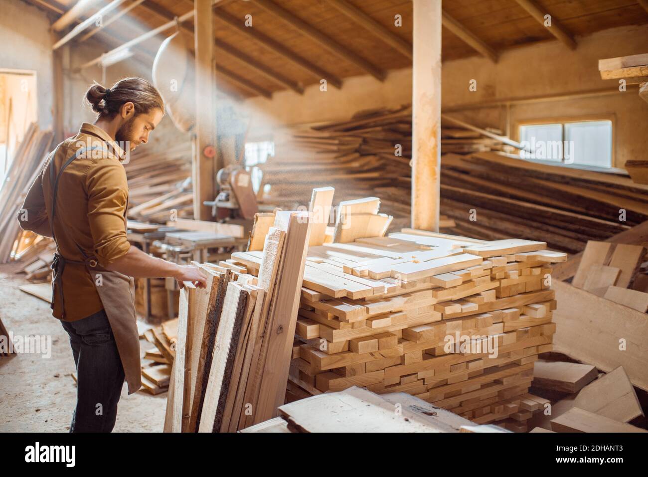 Carpenter or warehouse worker choosing raw wood material for the work ...