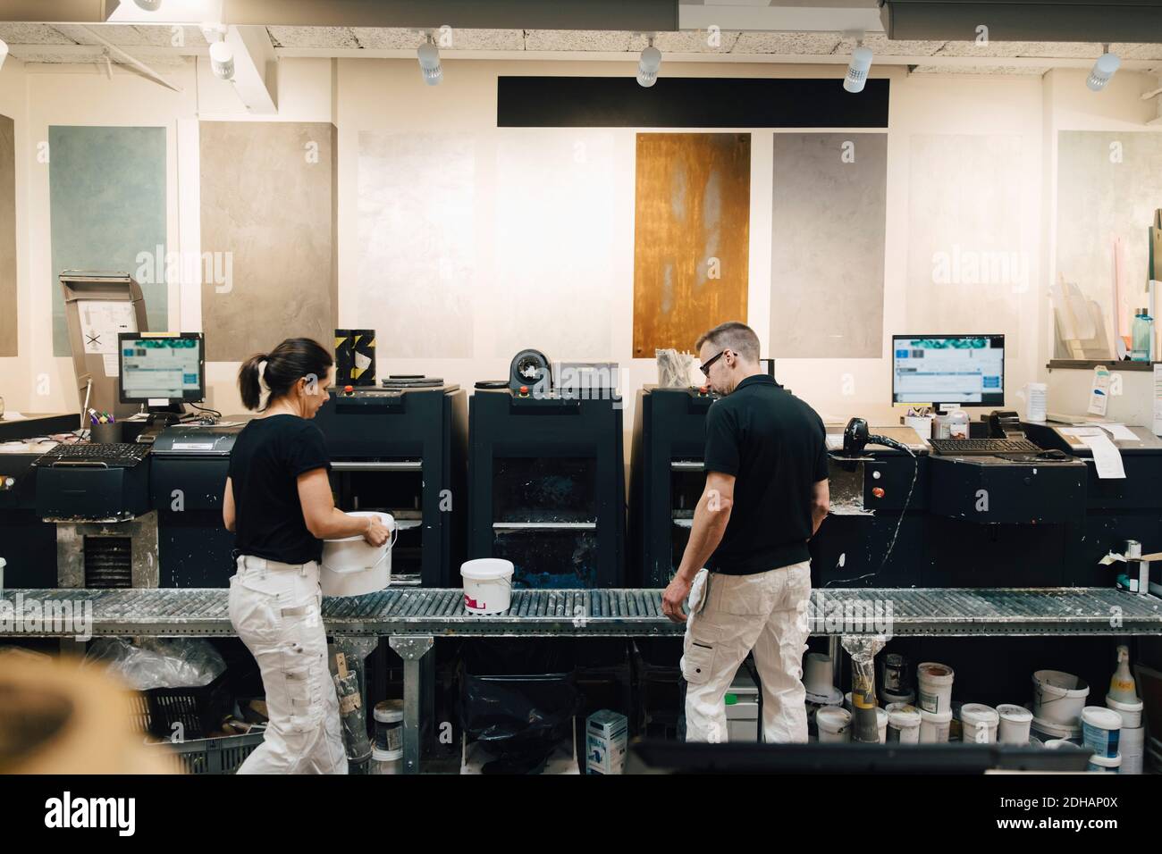 Female employee holding paint can while standing with coworker at store ...