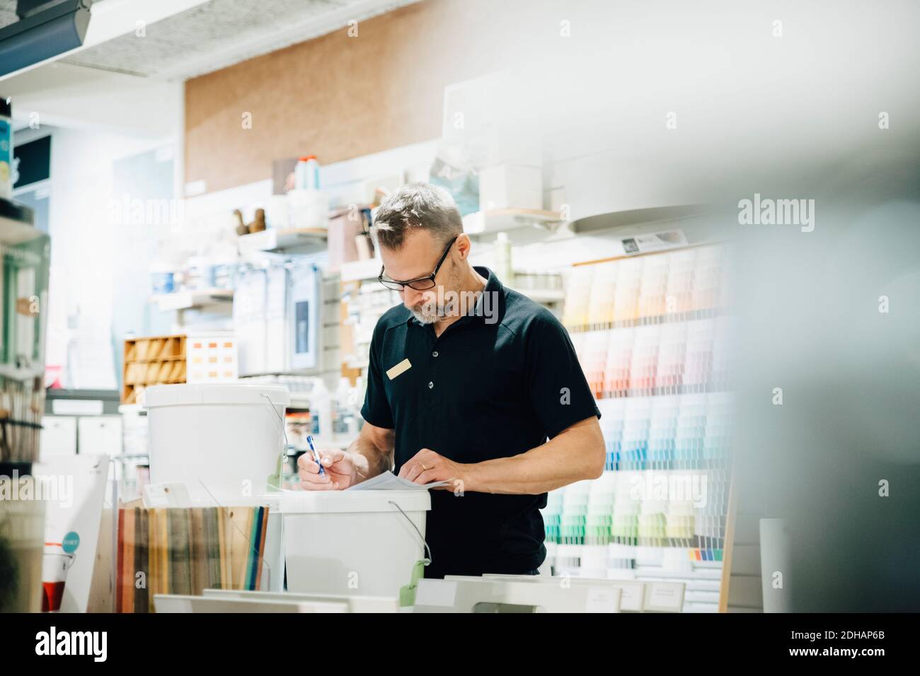 Salesman in uniform writing on document in hardware store Stock Photo ...