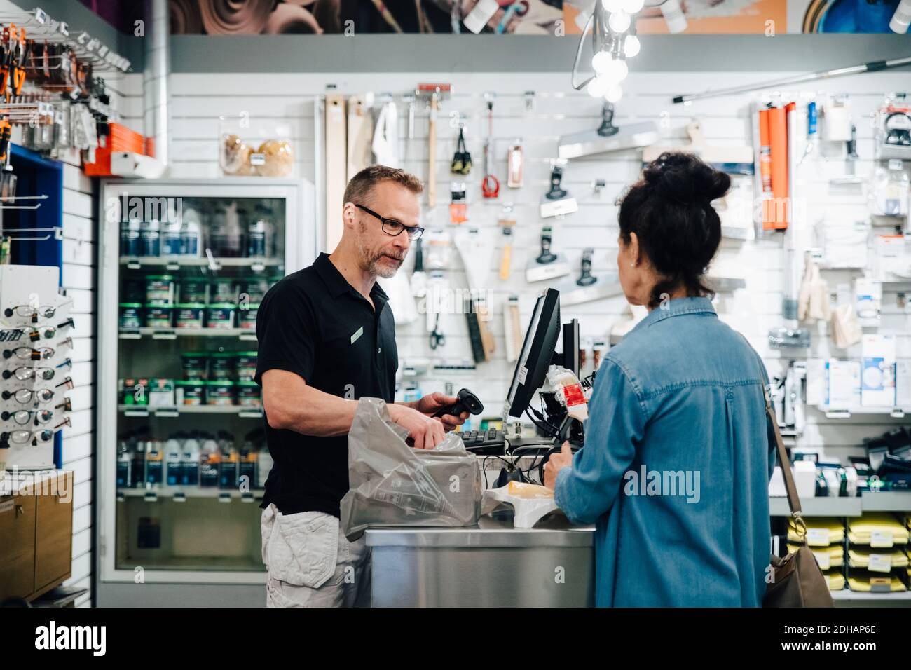 Female Customer talking with shop owner at checkout counter in store ...