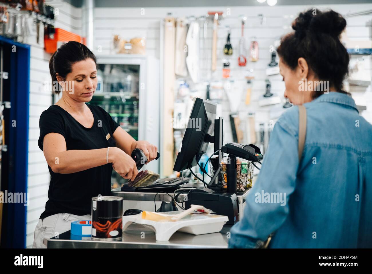 Cashier scanning paint brush while customer standing at checkout ...