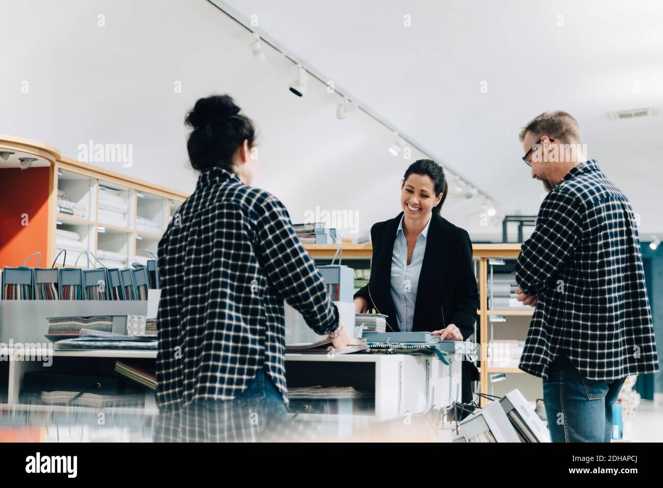 Sales employees assisting female customer in store Stock Photo - Alamy