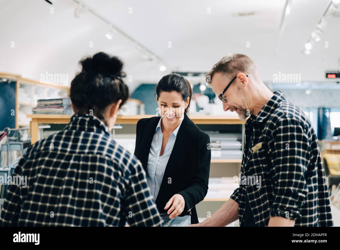 Male and female workers assisting female customer in store Stock Photo ...