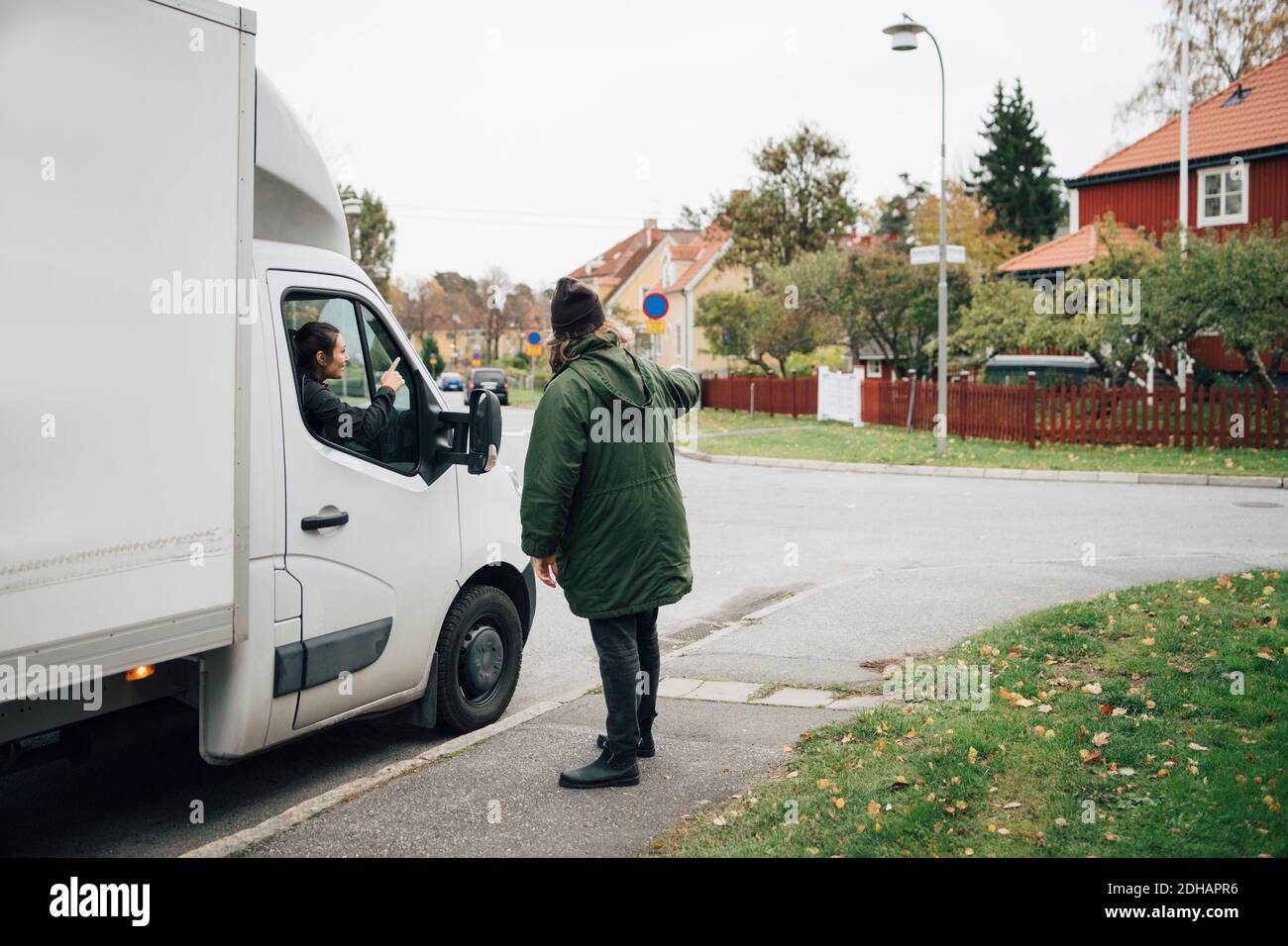 Man directing woman sitting in delivery van on street Stock Photo - Alamy