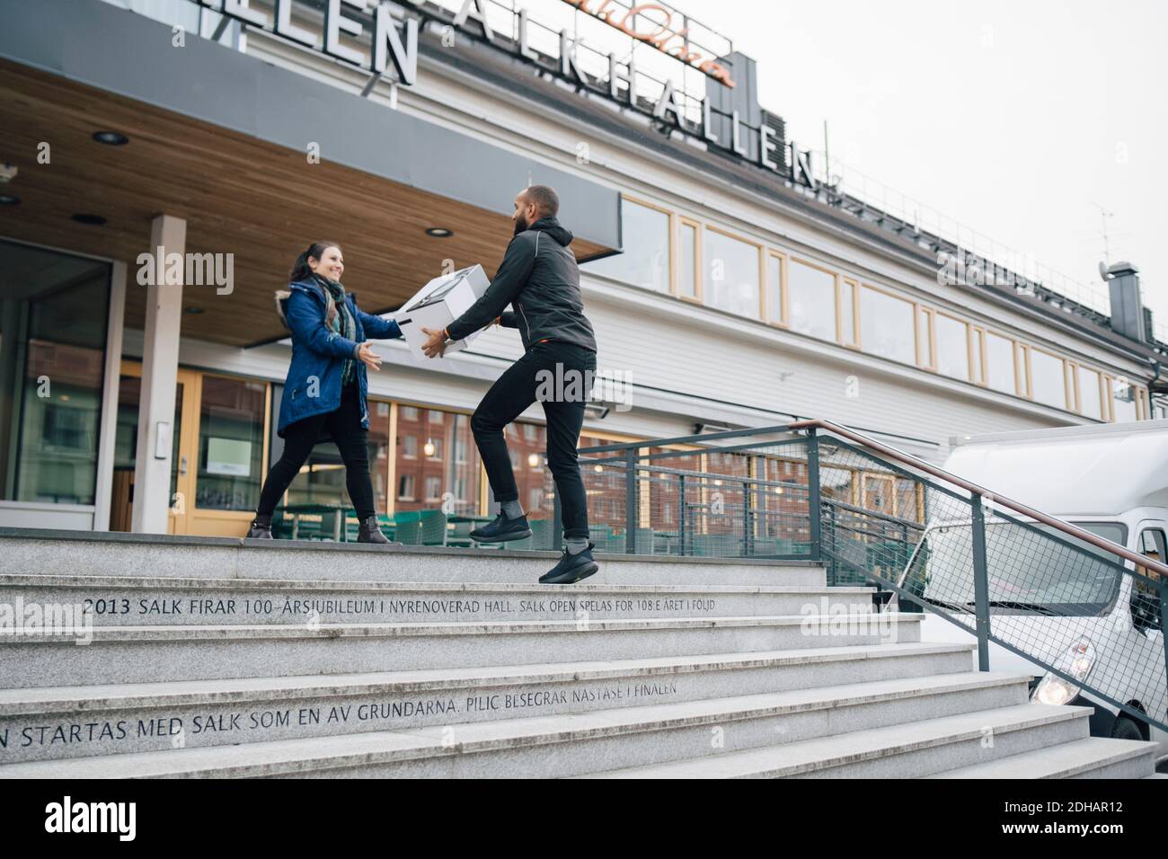 Low angle view of messenger delivering box to female customer in city ...