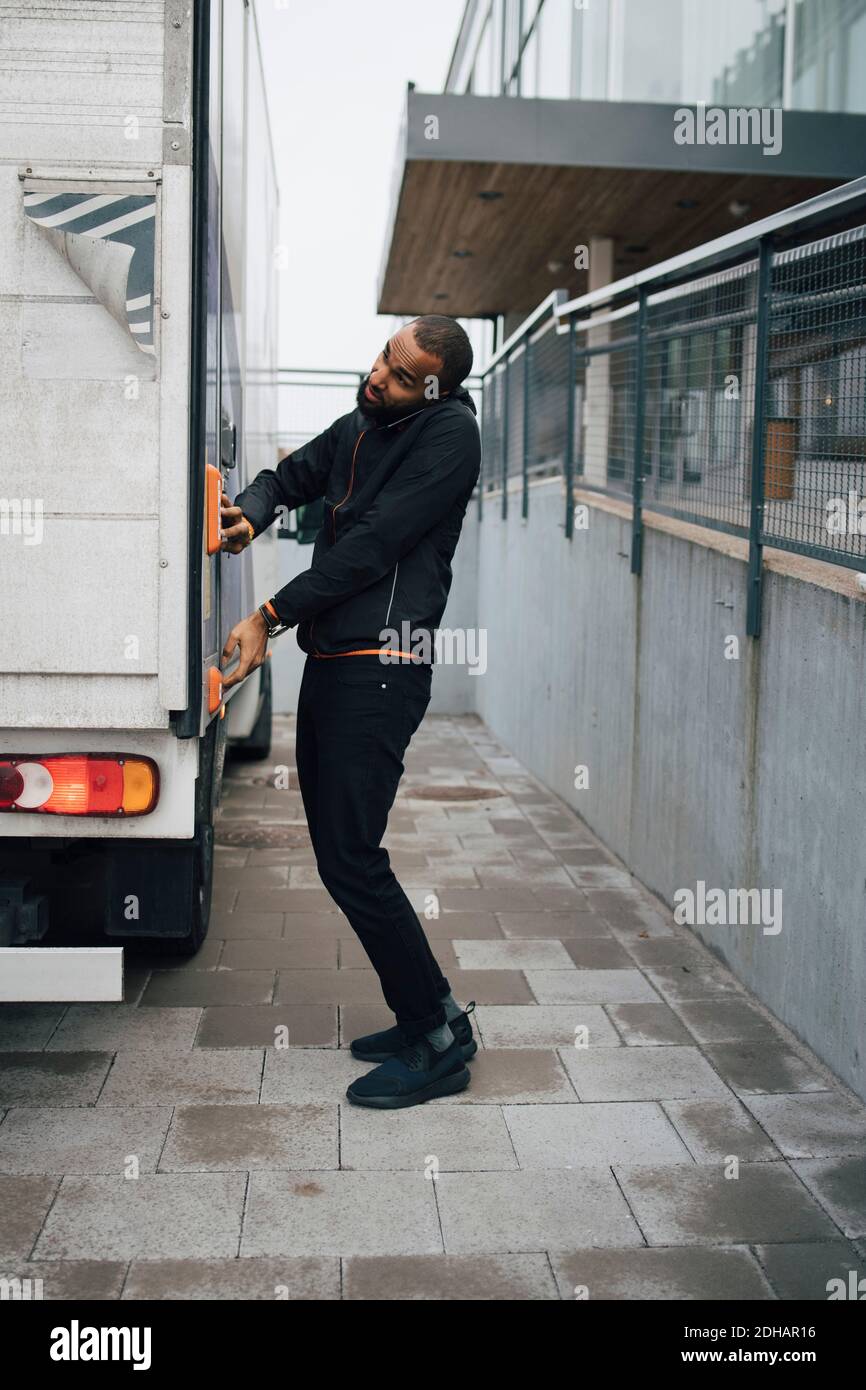 Full length of man talking through mobile phone while pushing button on ...