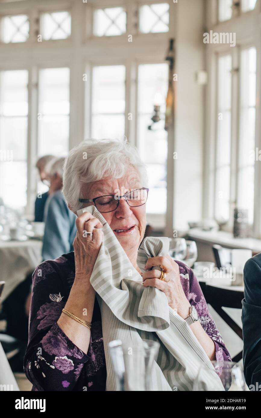 Senior woman crying while sitting in restaurant Stock Photo - Alamy