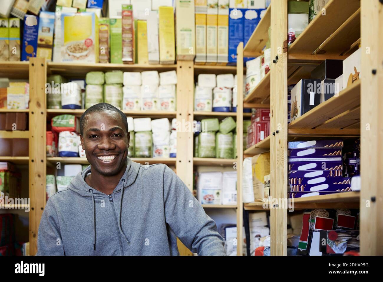Portrait of smiling mid adult worker against racks in warehouse Stock ...
