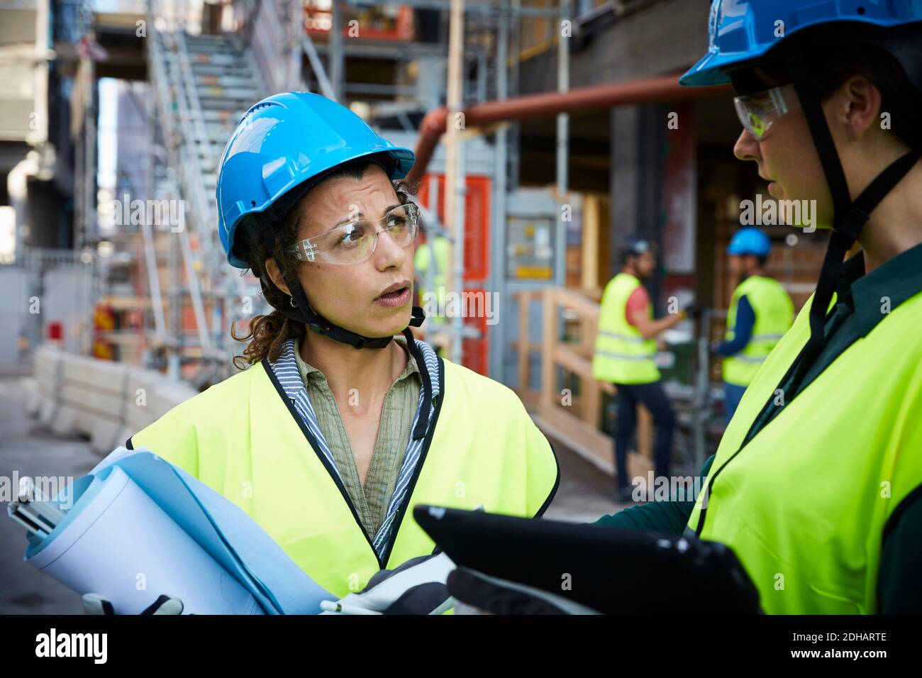 Female engineer discussing with coworker at construction site Stock ...