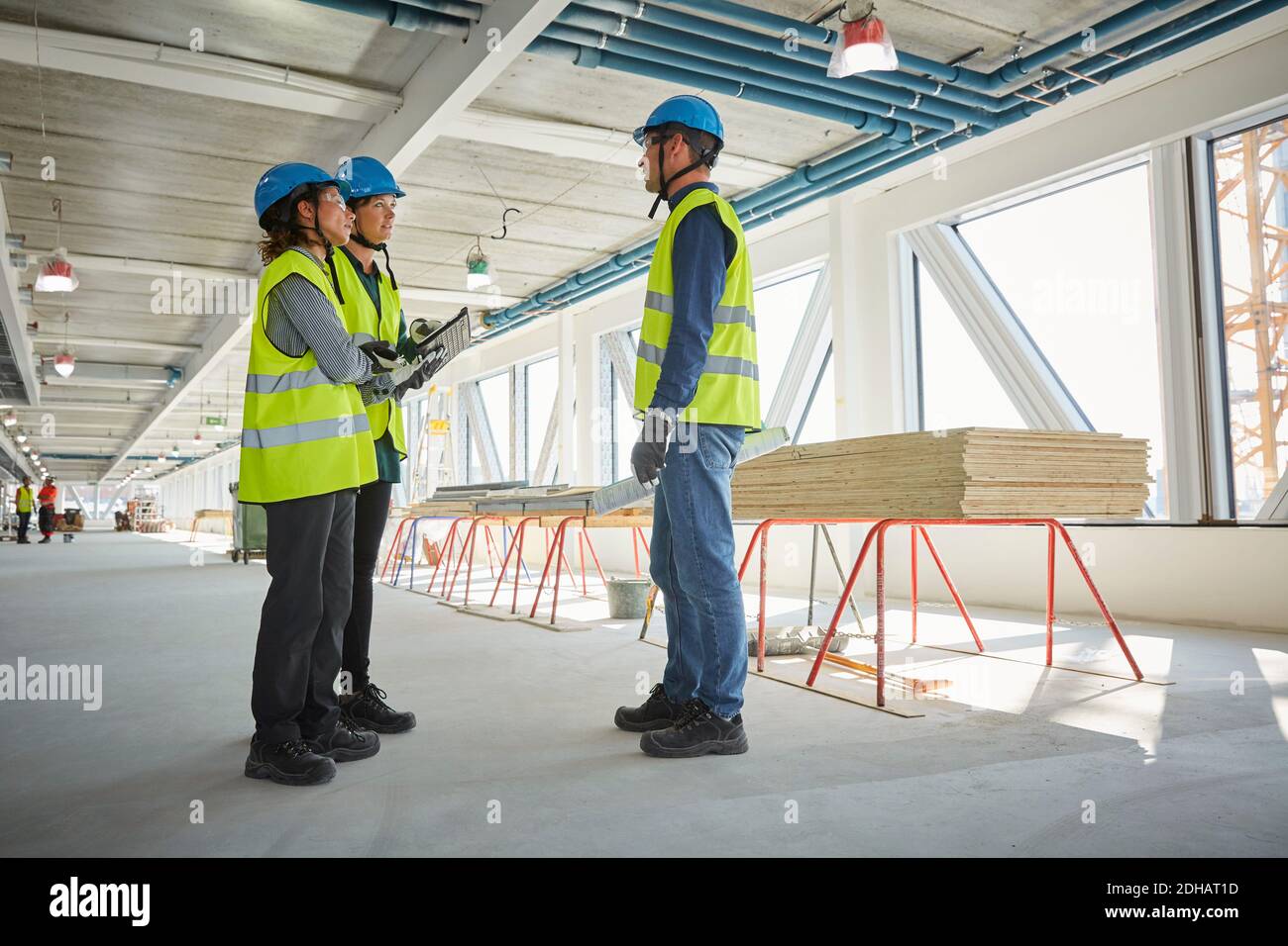 Full length of female and male engineers discussing at construction ...