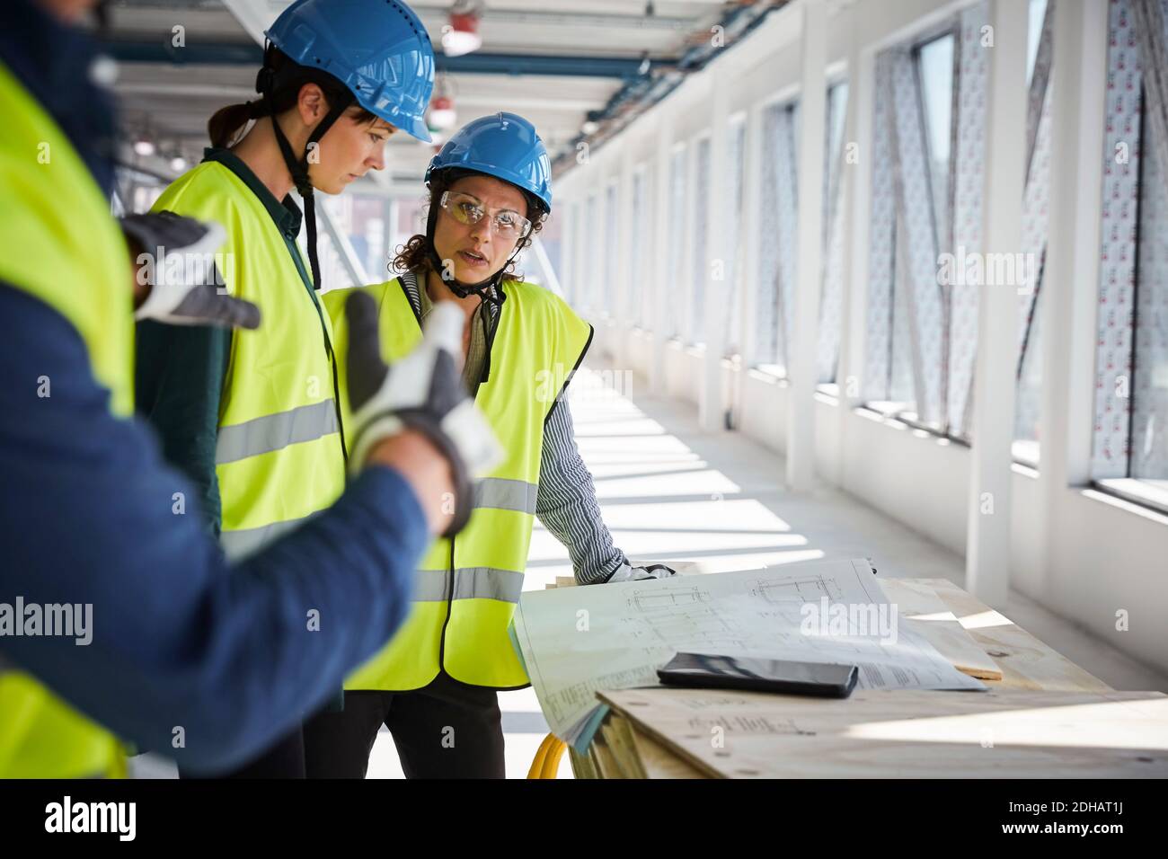 Female and male engineers discussing over blueprints at construction ...
